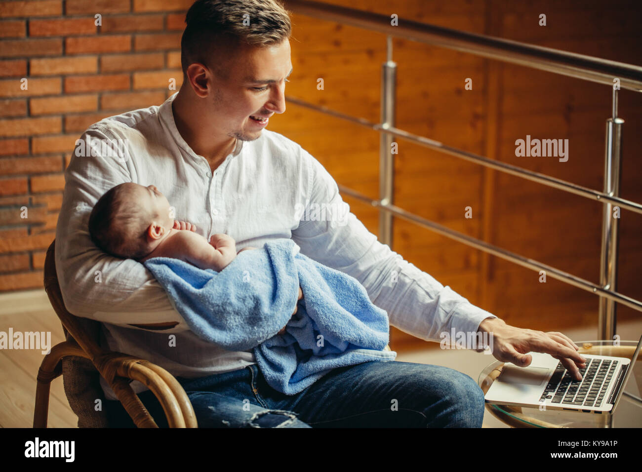 Father With Newborn Baby Working From Home Using Laptop Stock Photo - Alamy