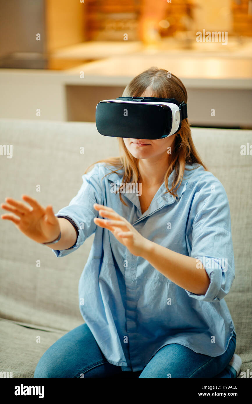 woman adjusting her VR headset and smiling while sitting on the carpet ...