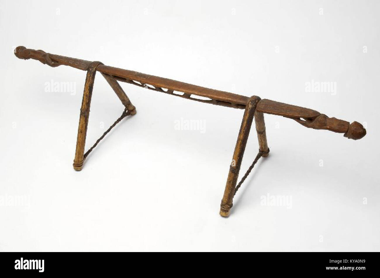 A wooden neck rest featuring intricate carvings of two human figures ...
