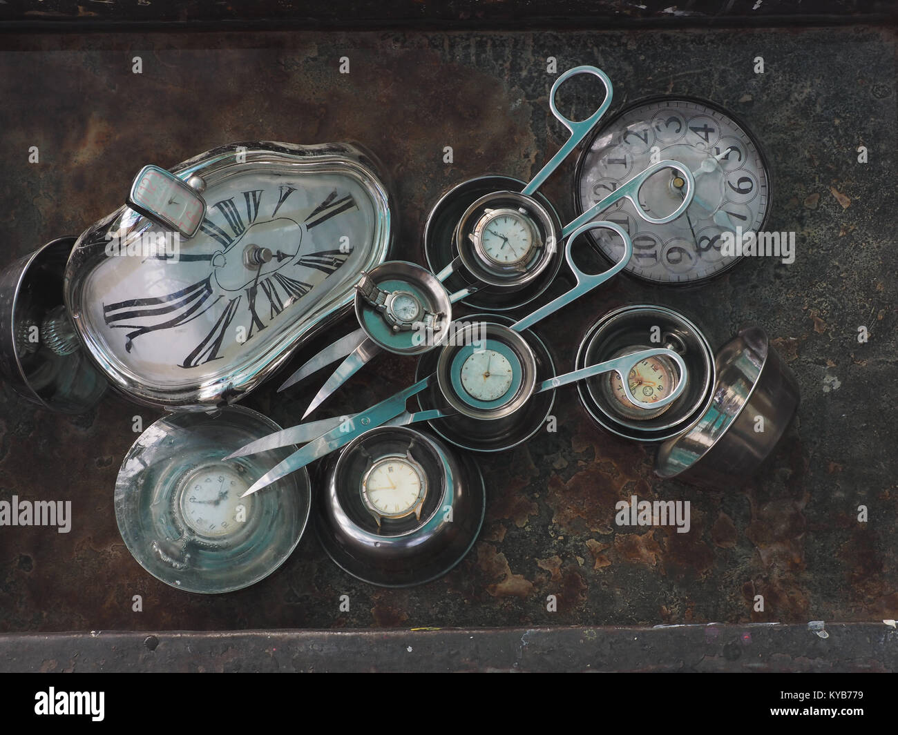 A pair of long curved scissors and watches of different sizes of ...