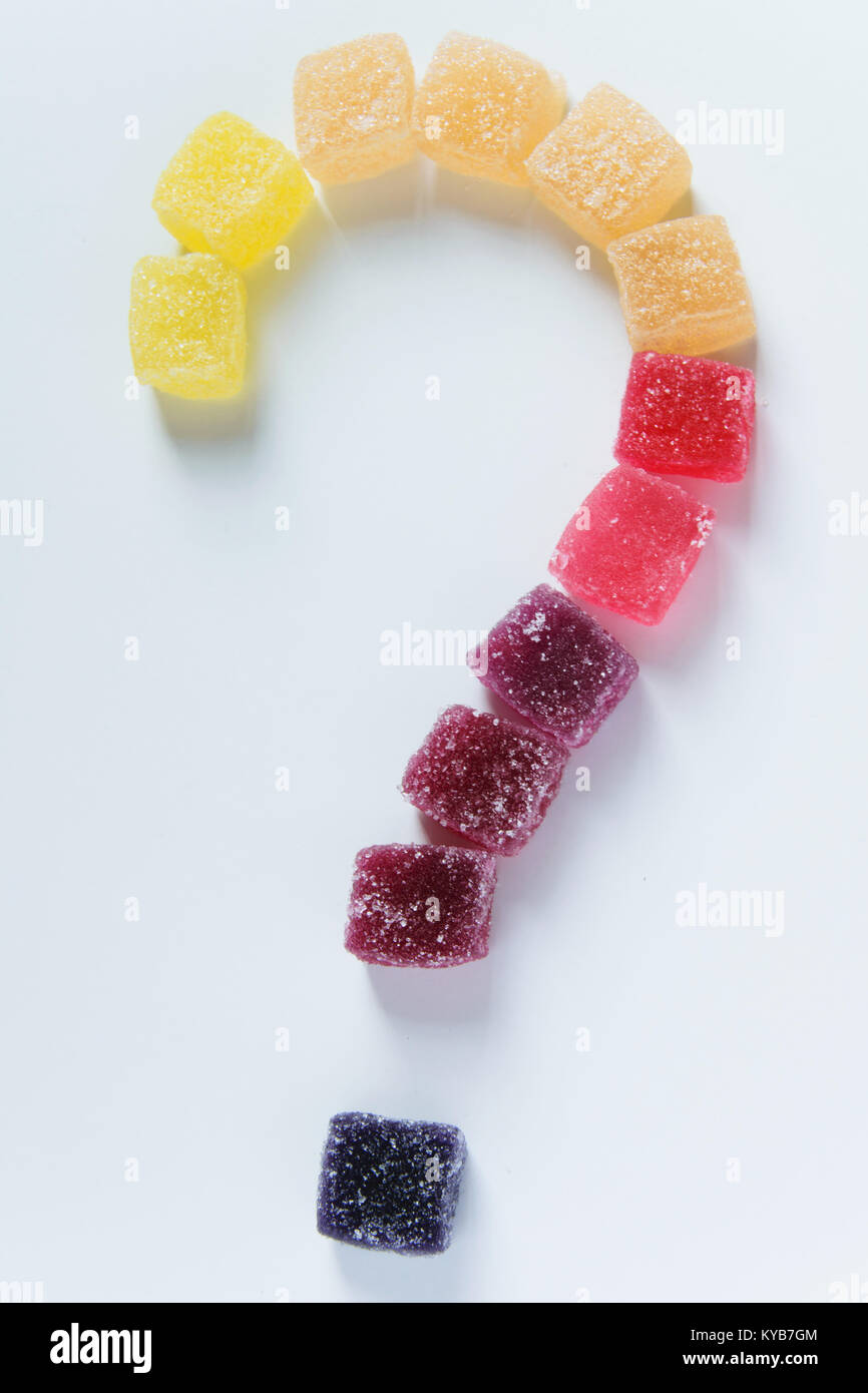 Yummy gummy candies on a white background in the shape of a question ...
