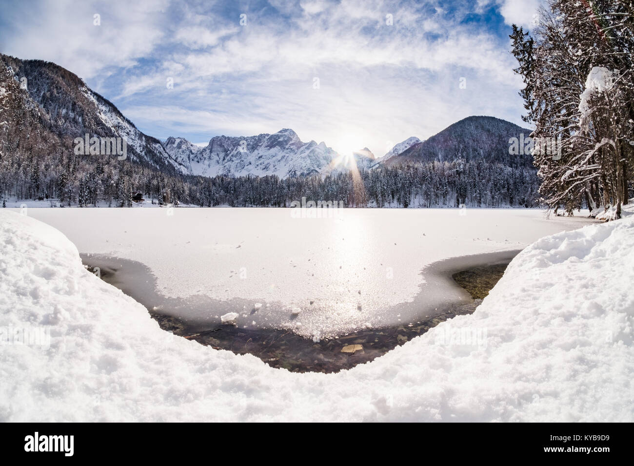 Mountain range Mangart seen from snow covert frozen lake Fusine with ...