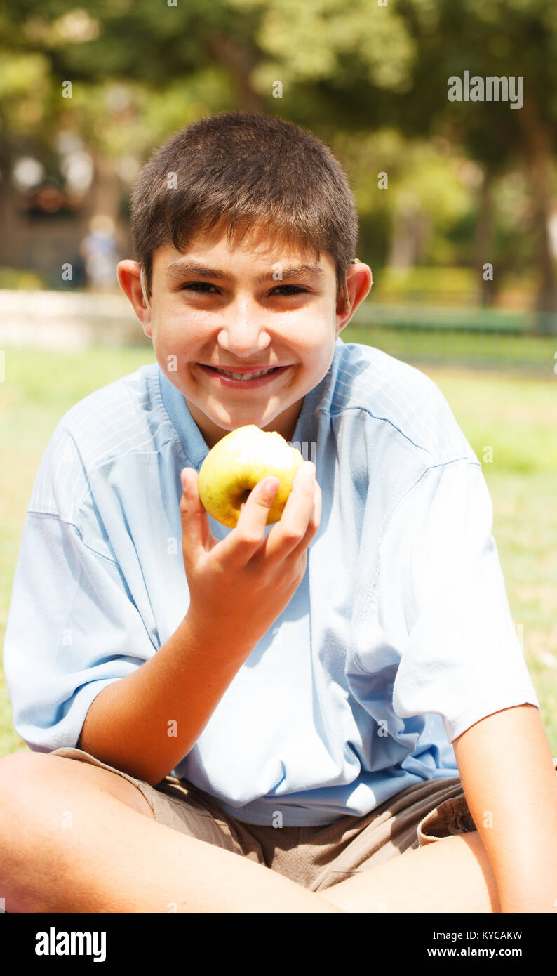 Teenage Boy eating green apple with Facial Expression Stock Photo - Alamy