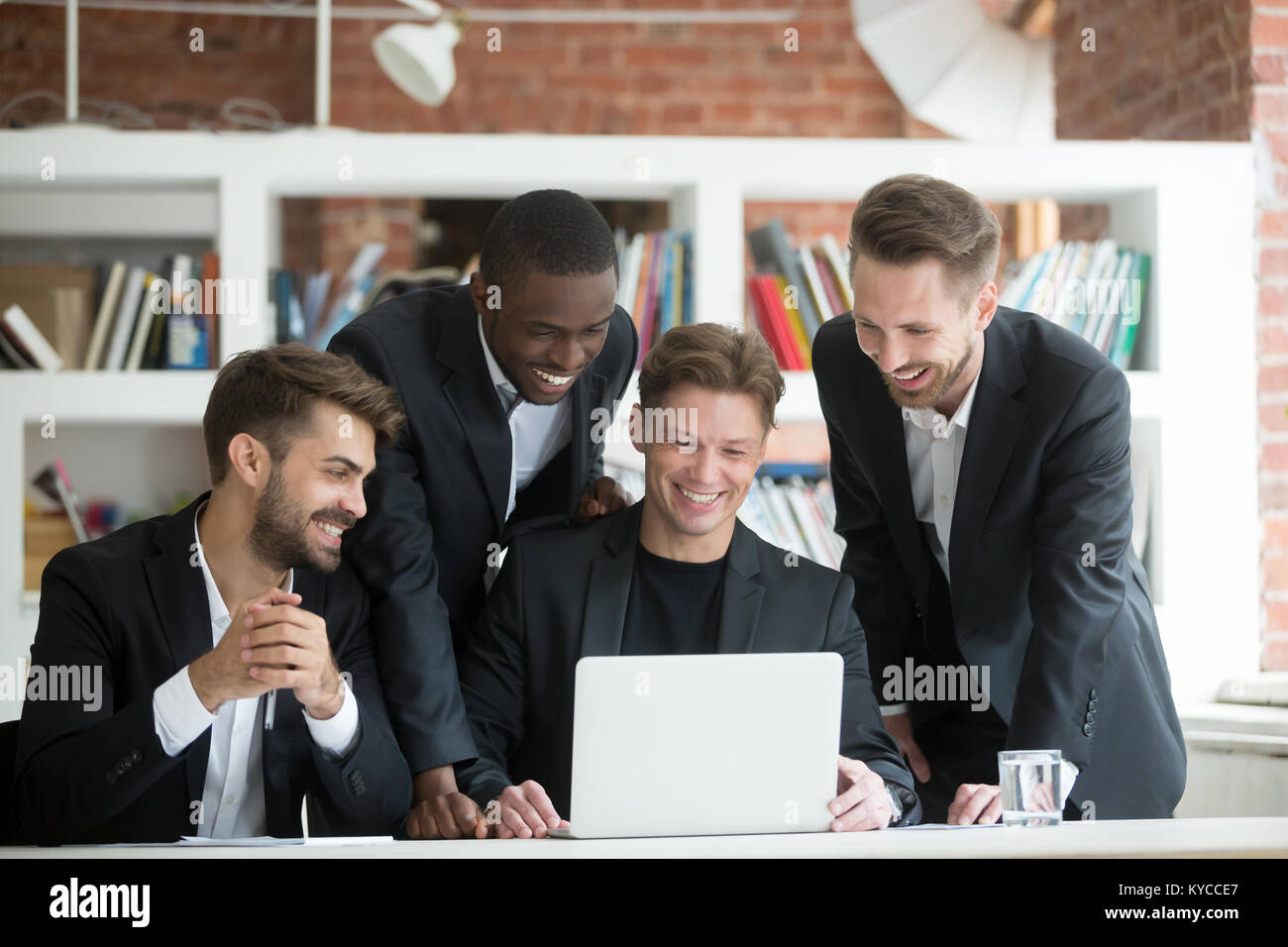 Multi-ethnic smiling businessmen in suits watching something funny on ...