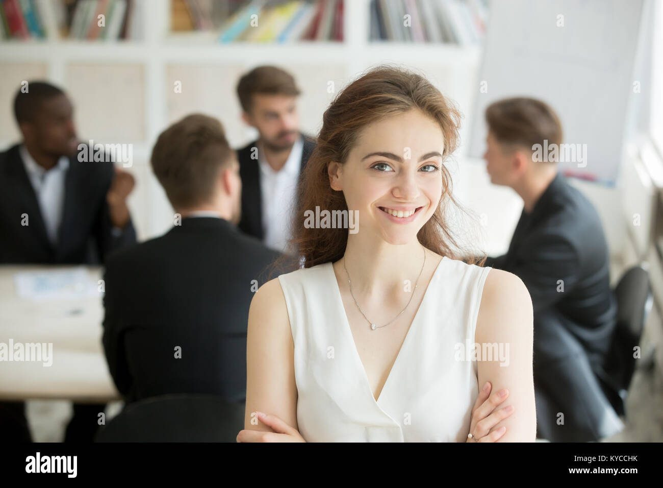 Attractive female leader standing with arms crossed in front of male ...
