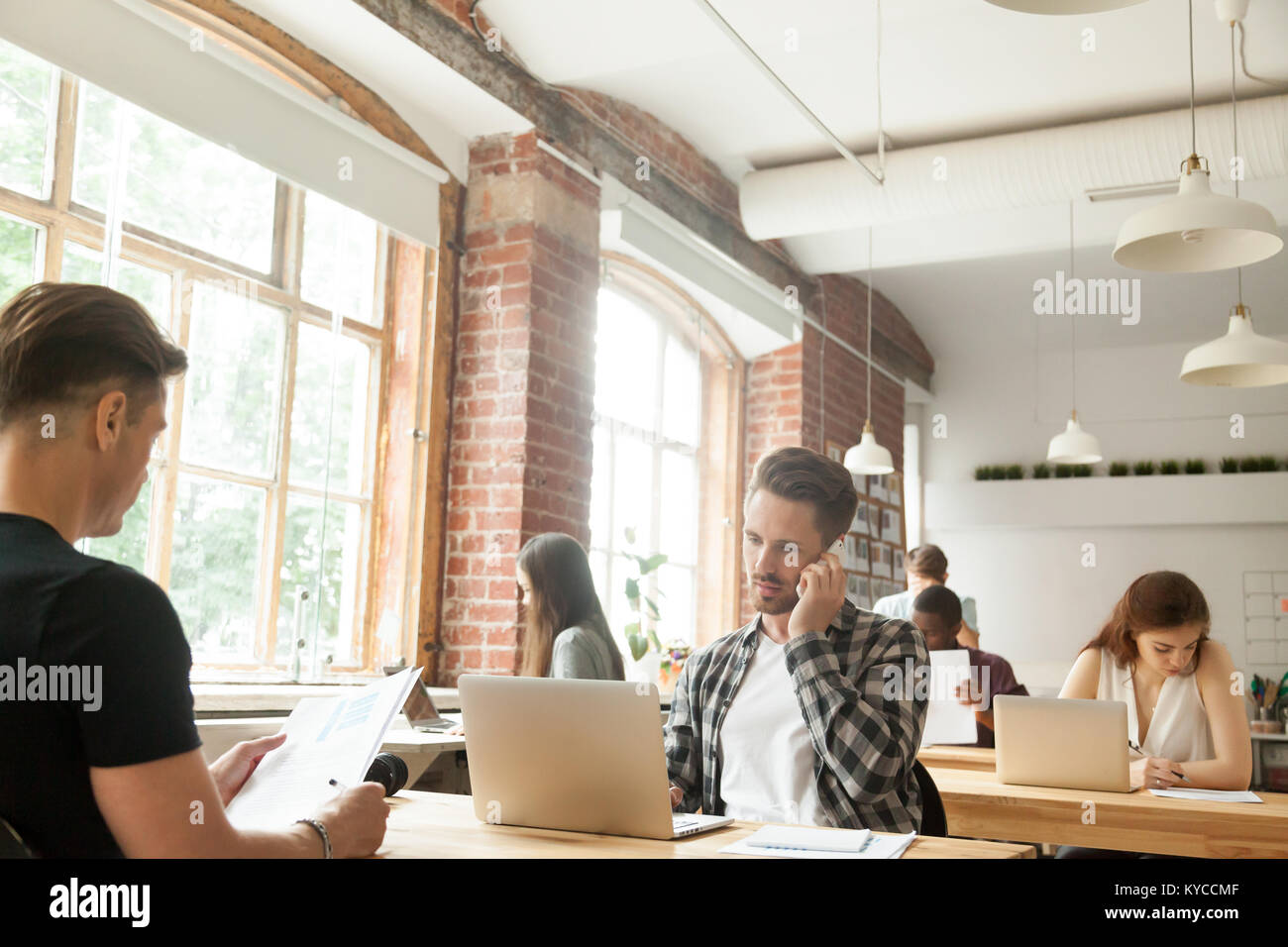 Diverse people focused on work in modern loft co-working space interior ...