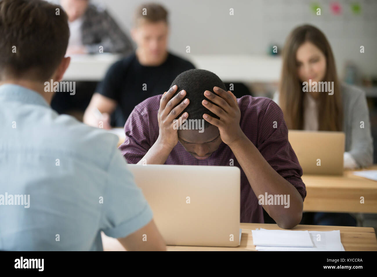 Frustrated african office worker having work problem holding head in ...