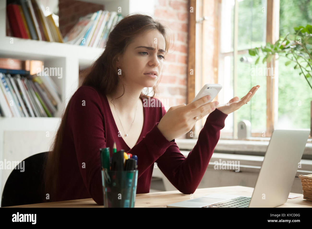 Frustrated woman having problem with not working smart phone sitting at ...
