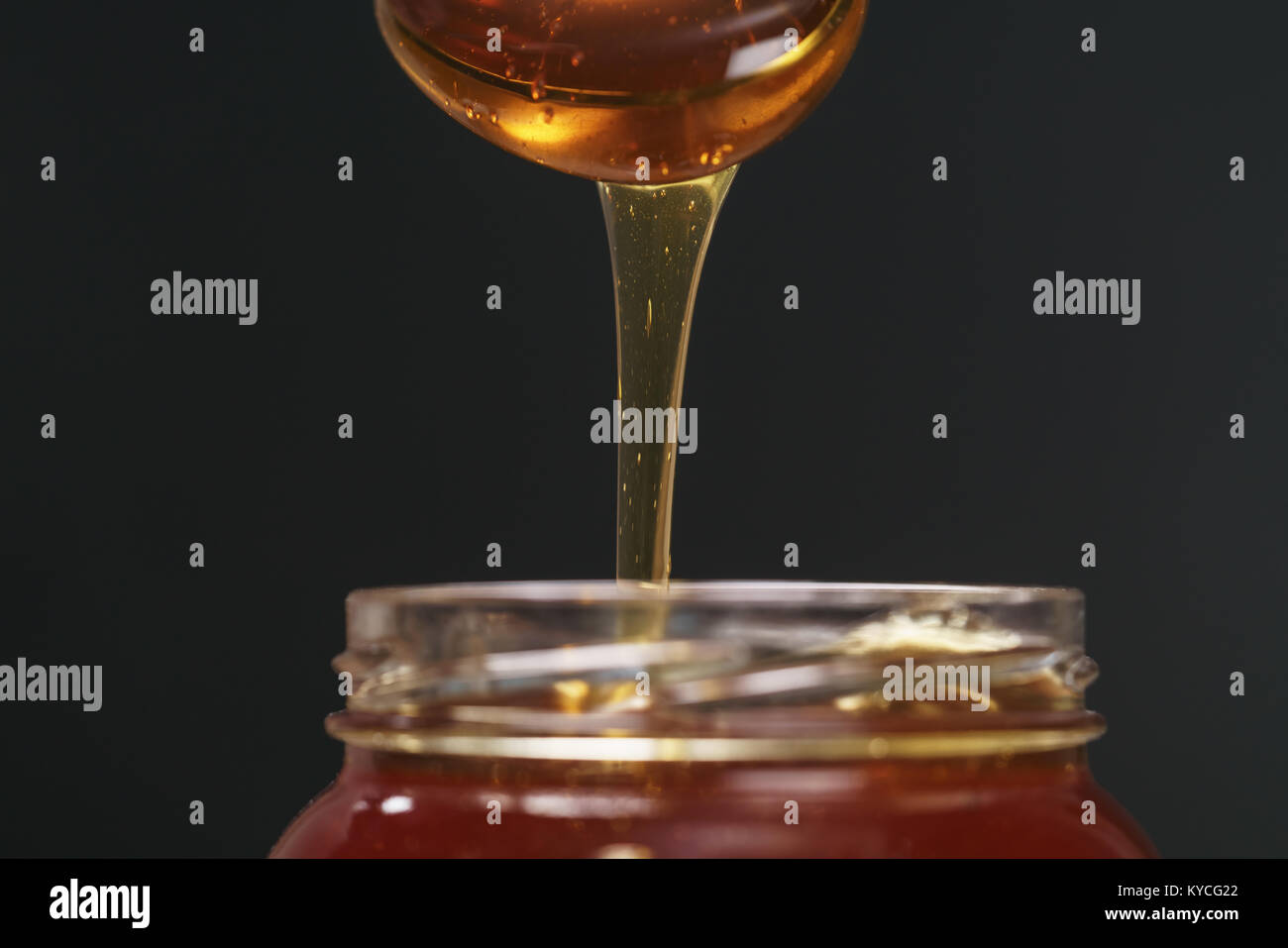 scooping organic honey with spoon from glass jar, closeup Stock Photo ...