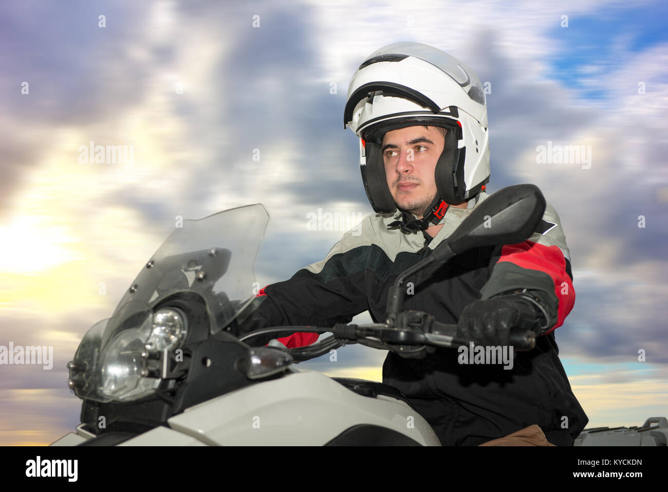 a young man sits on a motorcycle and has a helmet on his head Stock ...