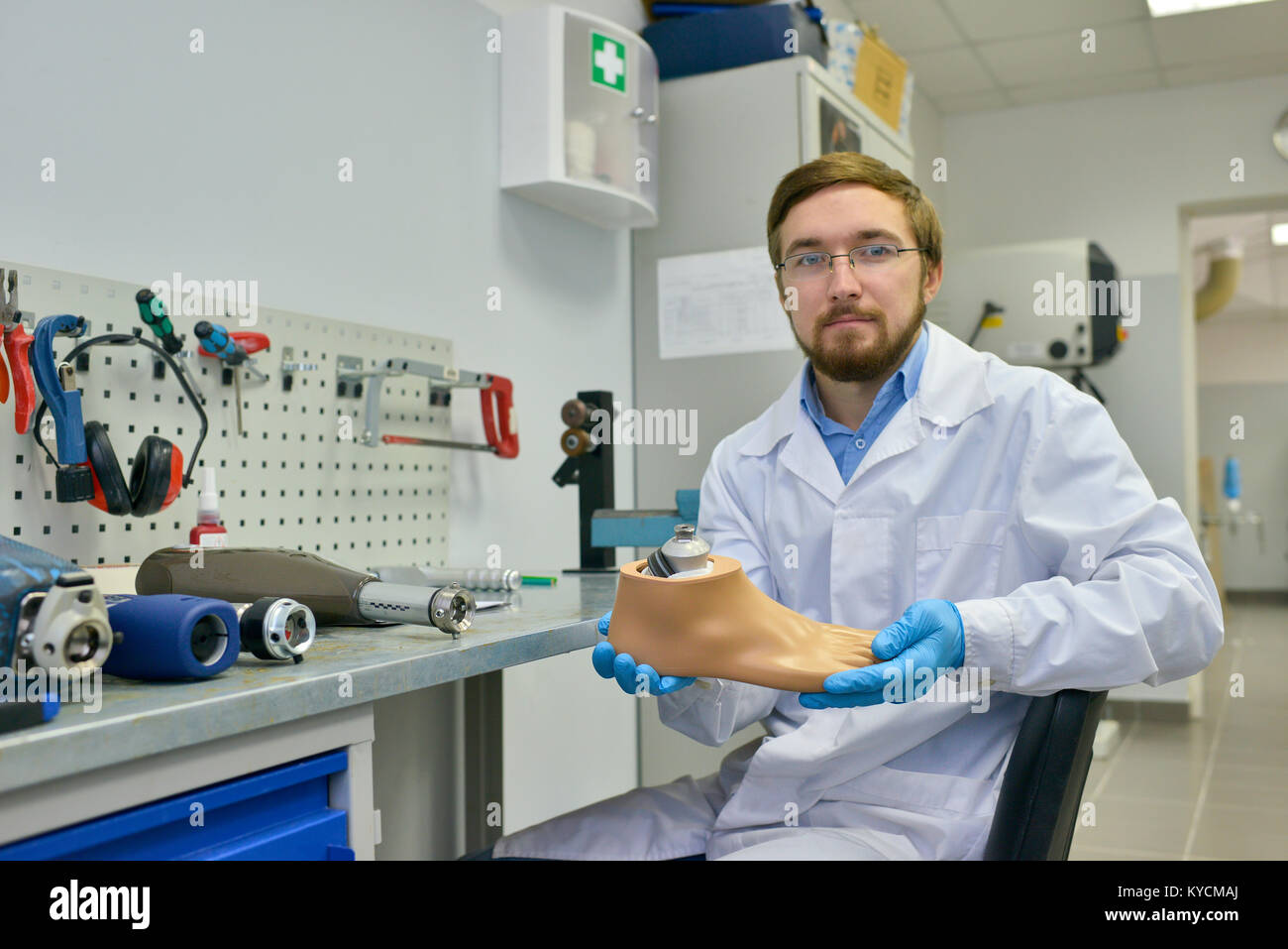 Portrait of young medical engineer posing in laboratory sitting by ...