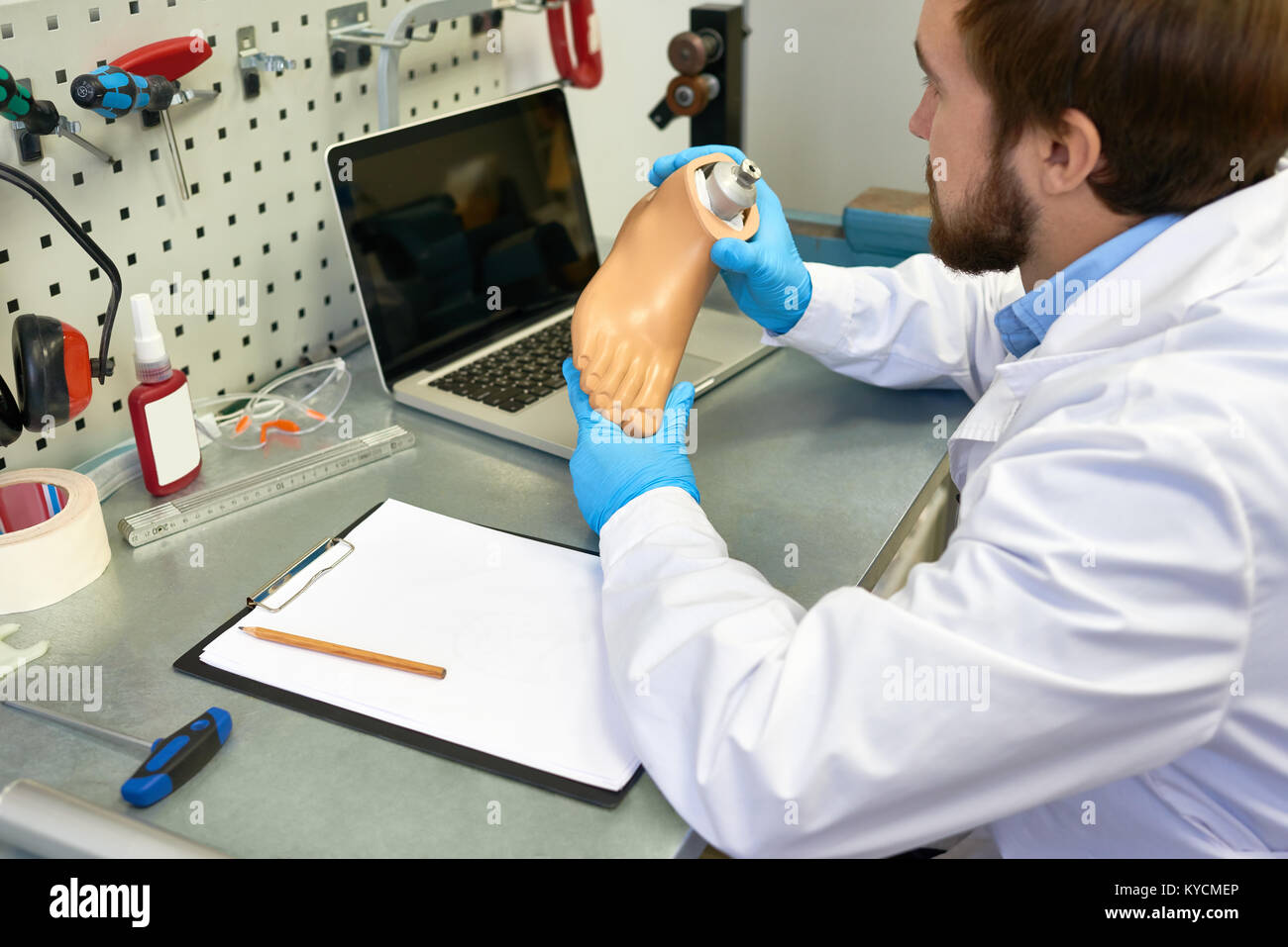 Portrait of young prosthetist holding prosthetic leg checking it for ...