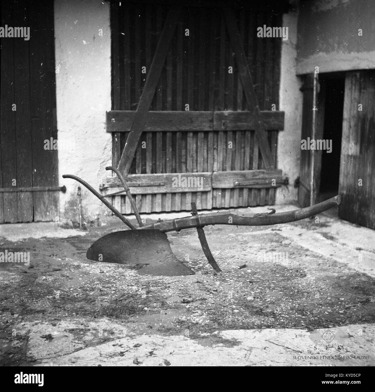 A 1955 photograph of an iron-headed plow with wooden handles, illustrating traditional mid-20th ...
