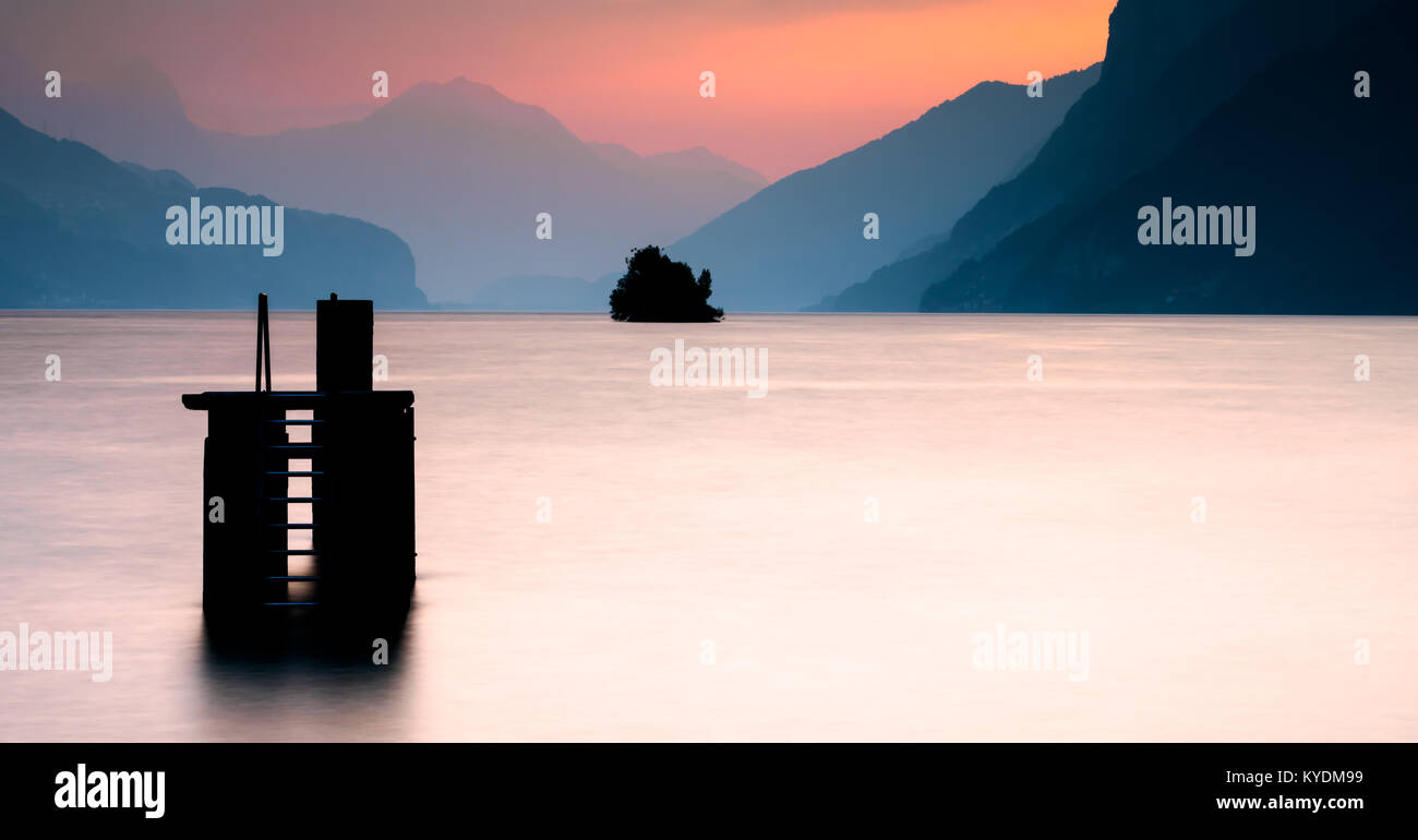 beautiful sunset over a mountain lake with a diving platform in the ...