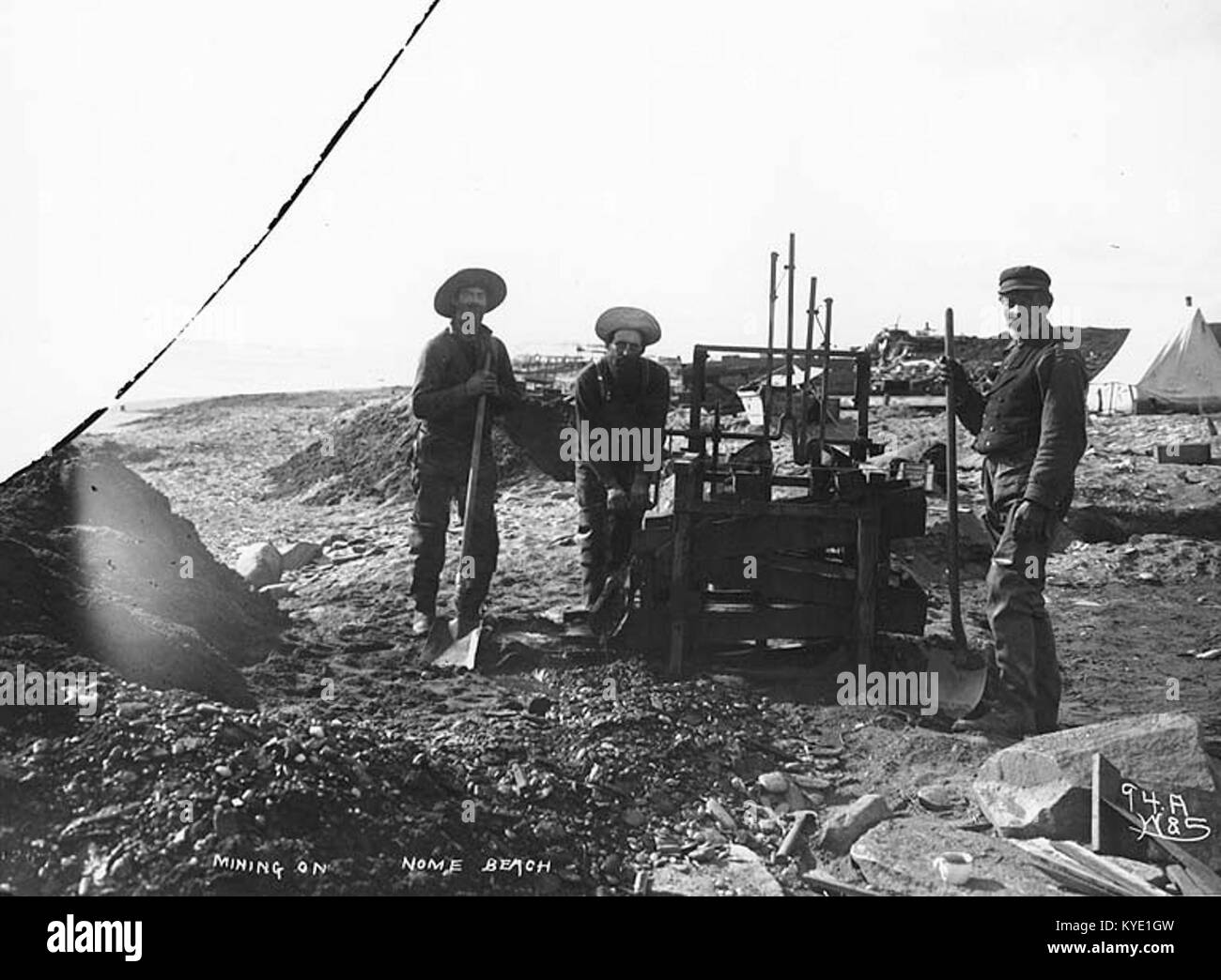 Black-and-white photograph of three men mining for gold on Nome Beach ...