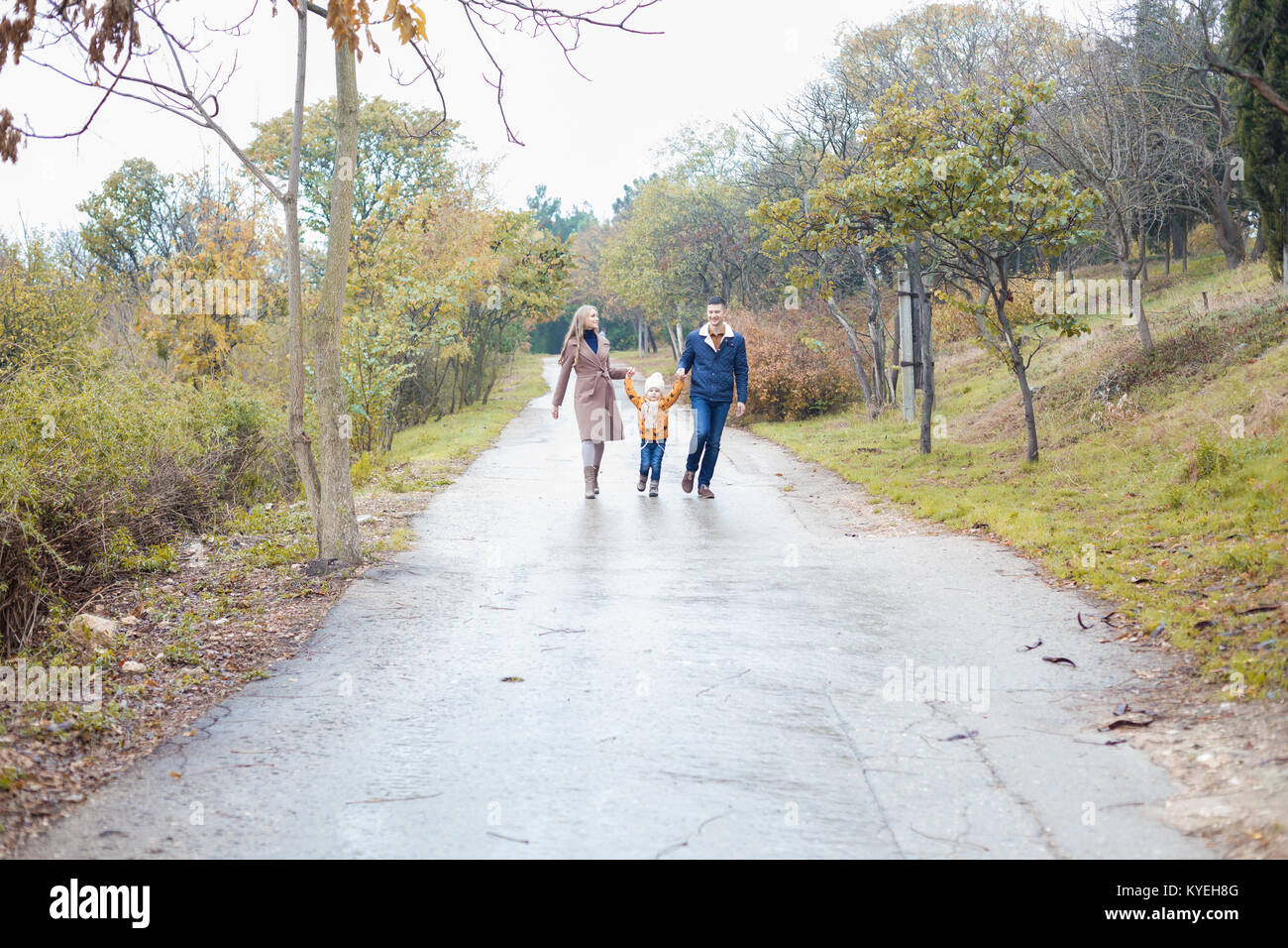 a family with a son go on road in the rain Stock Photo - Alamy