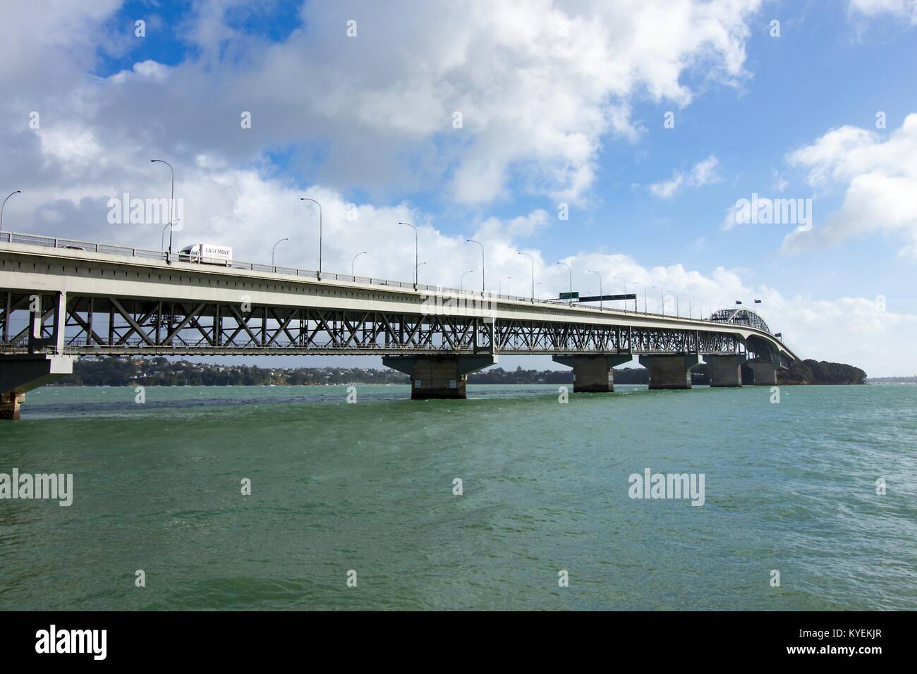 Auckland Harbor Bridge under a cloudy blue sky in downtown Auckland ...
