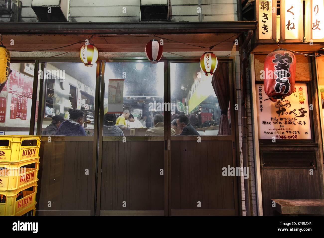 People are visible dining in a small restaurant, through a window, in ...