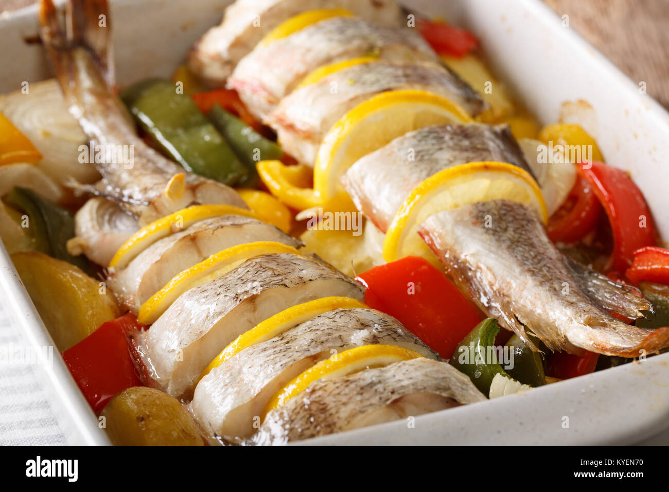 Atlantic cod baked with vegetables in a baking dish close up on a table ...