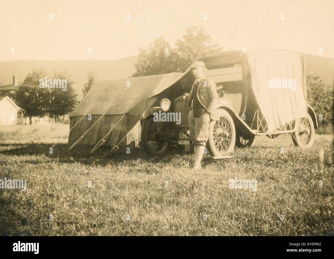 A man wearing formal attire poses beside his automobile and car camping ...