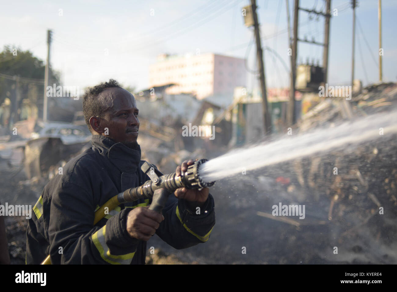 A photograph showing a firefighter spraying water at a fire caused by a ...
