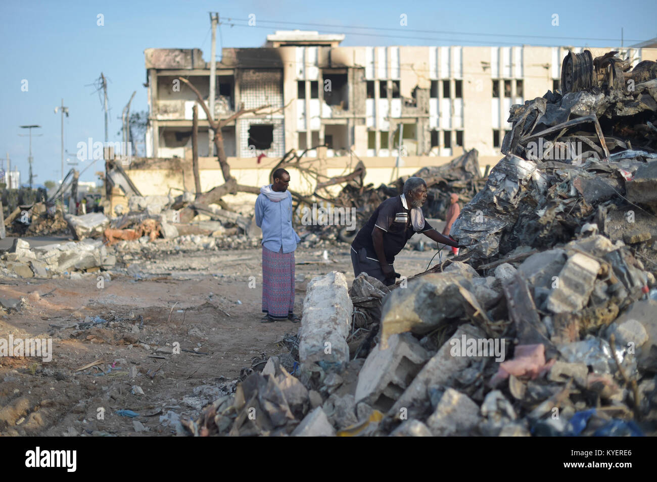 Two men inspect the wreckage of a building after a VBIED (Vehicle-Borne ...