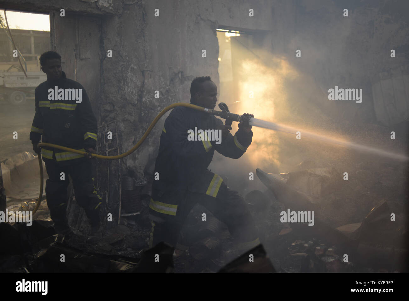 A photo showing a firefighter spraying water at the site of a VBIED ...