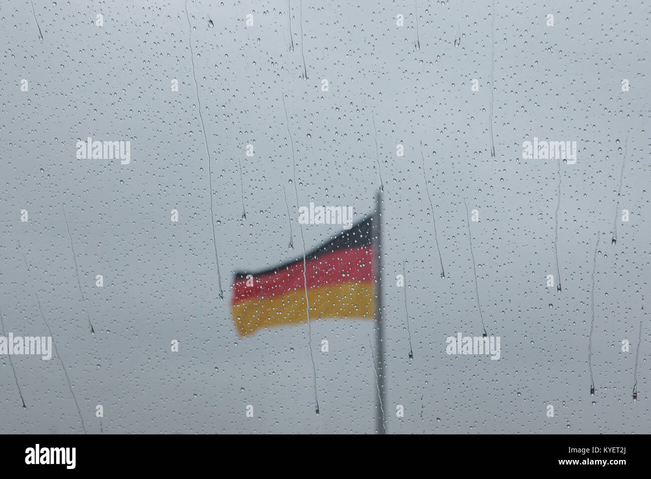 German national flag pictured through raindrops on the glass from ...
