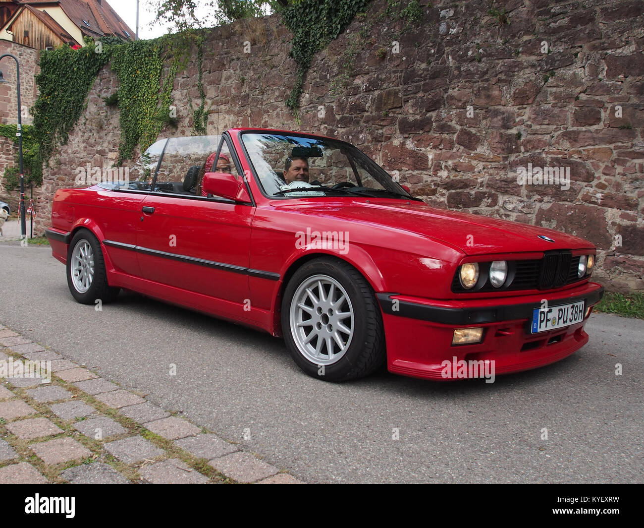 A photograph of a red BMW car driving around a castle in 2017. The ...