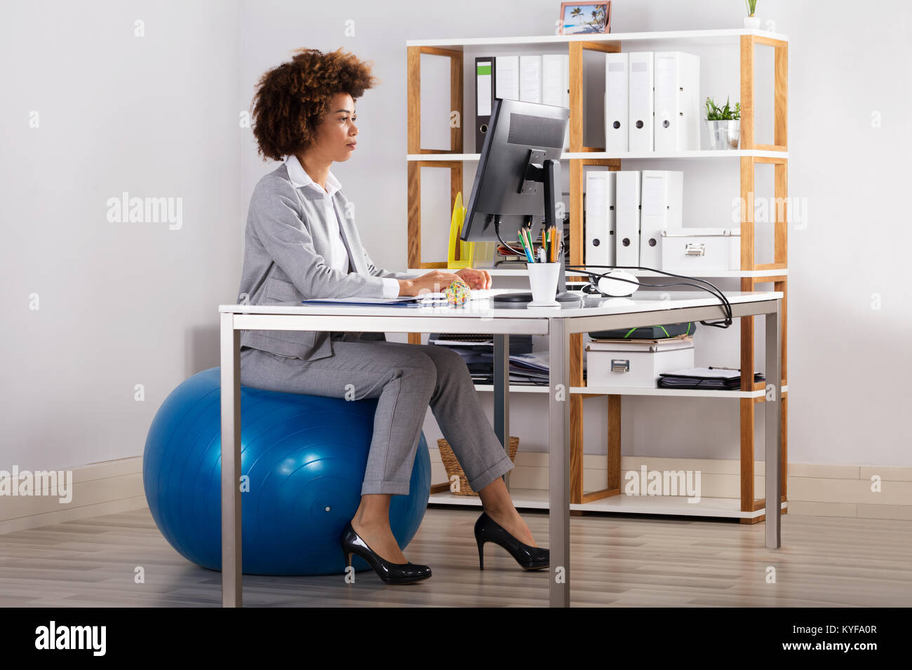 Young Businesswoman Using Computer While Sitting On Fitness Ball In ...