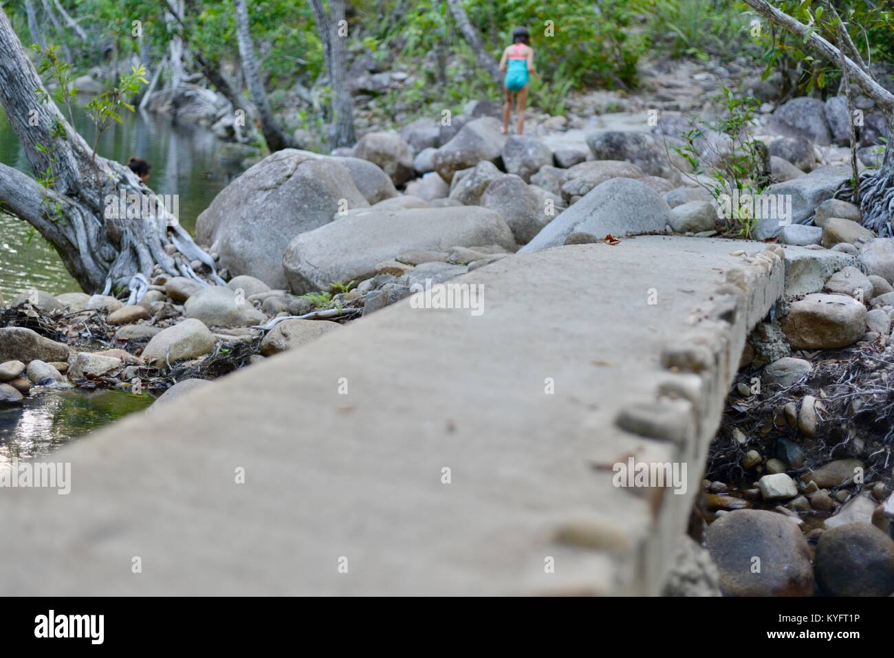 Child crossing a concrete footbridge crossing a stream after having a ...