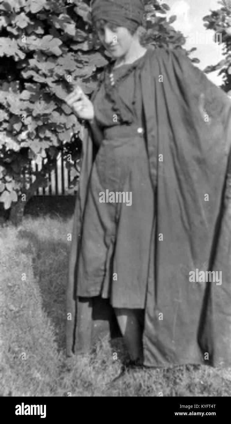 This image depicts a woman dressed in a formal gown, cloak, and turban ...