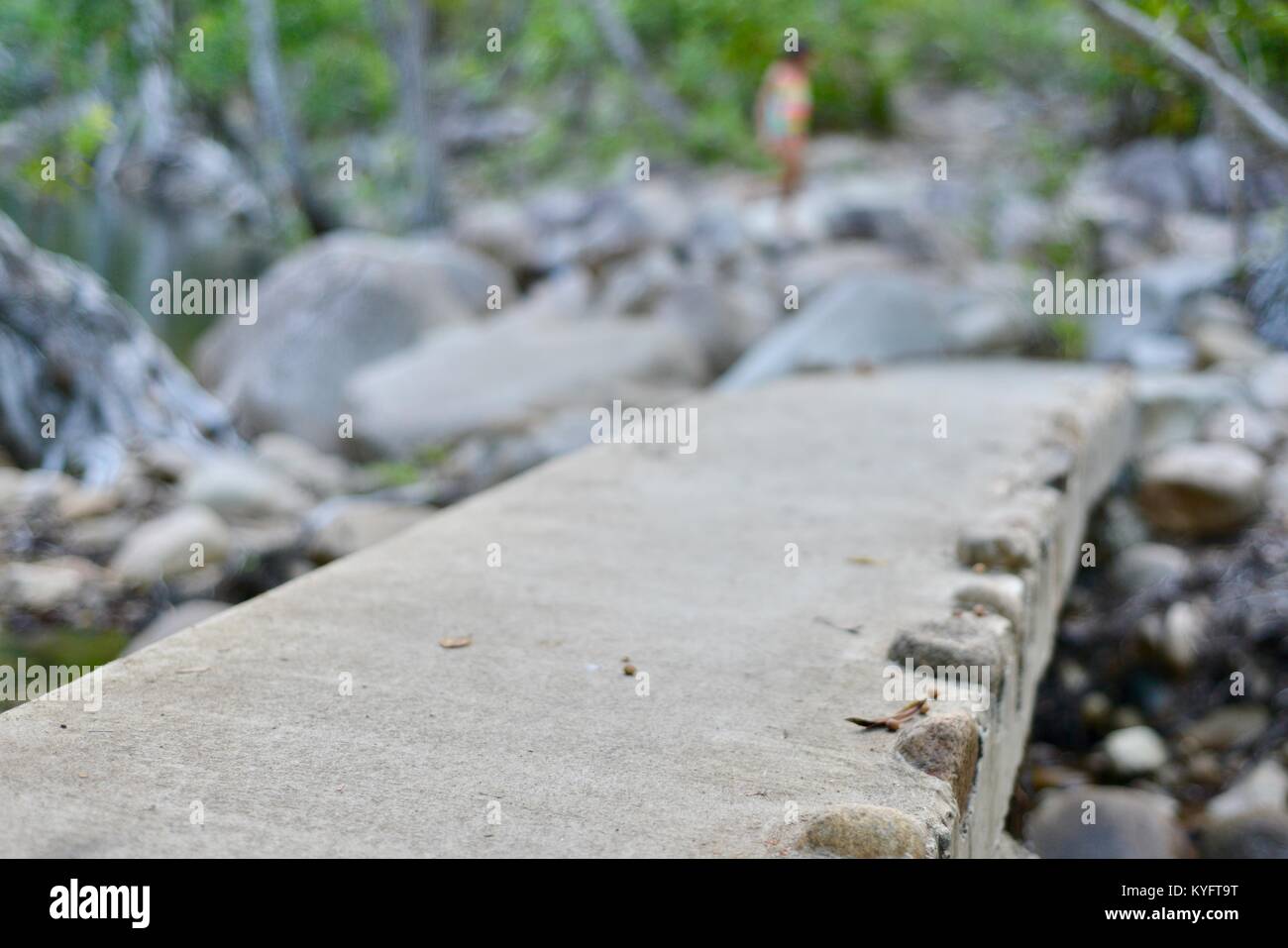 Child crossing a concrete footbridge crossing a stream after having a ...
