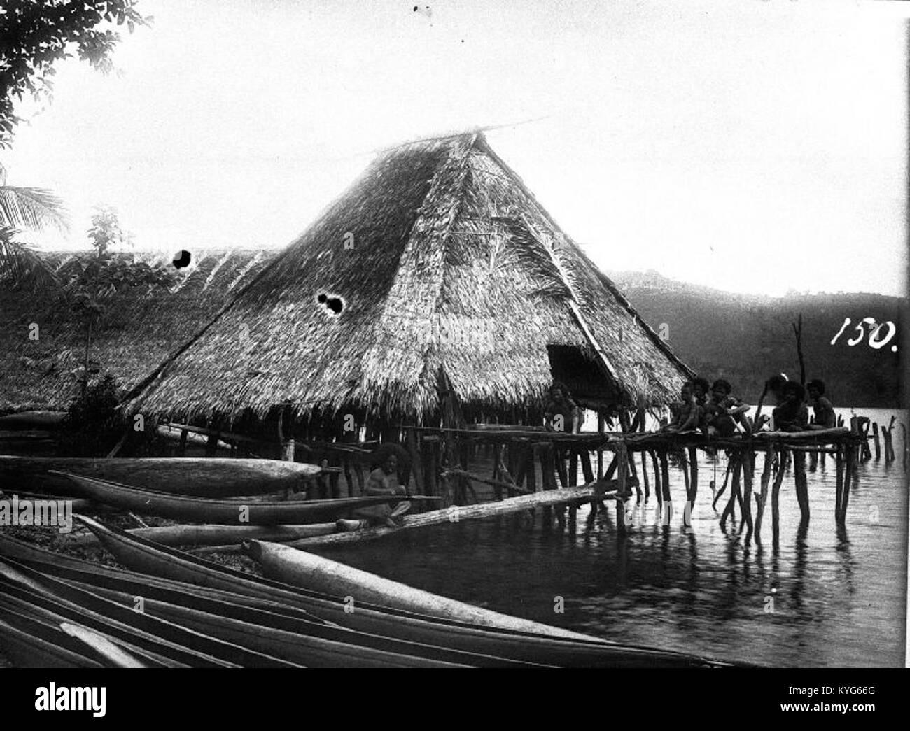 A photograph of traditional wooden proas in front of a men's house ...