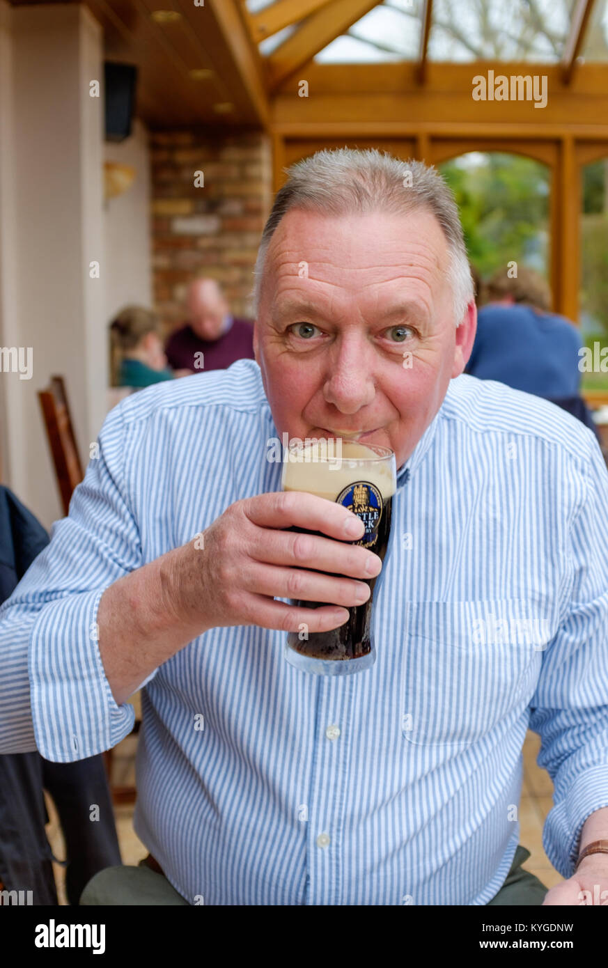 Happy man drinking a pint of draught beer from a pint glass in doors ...