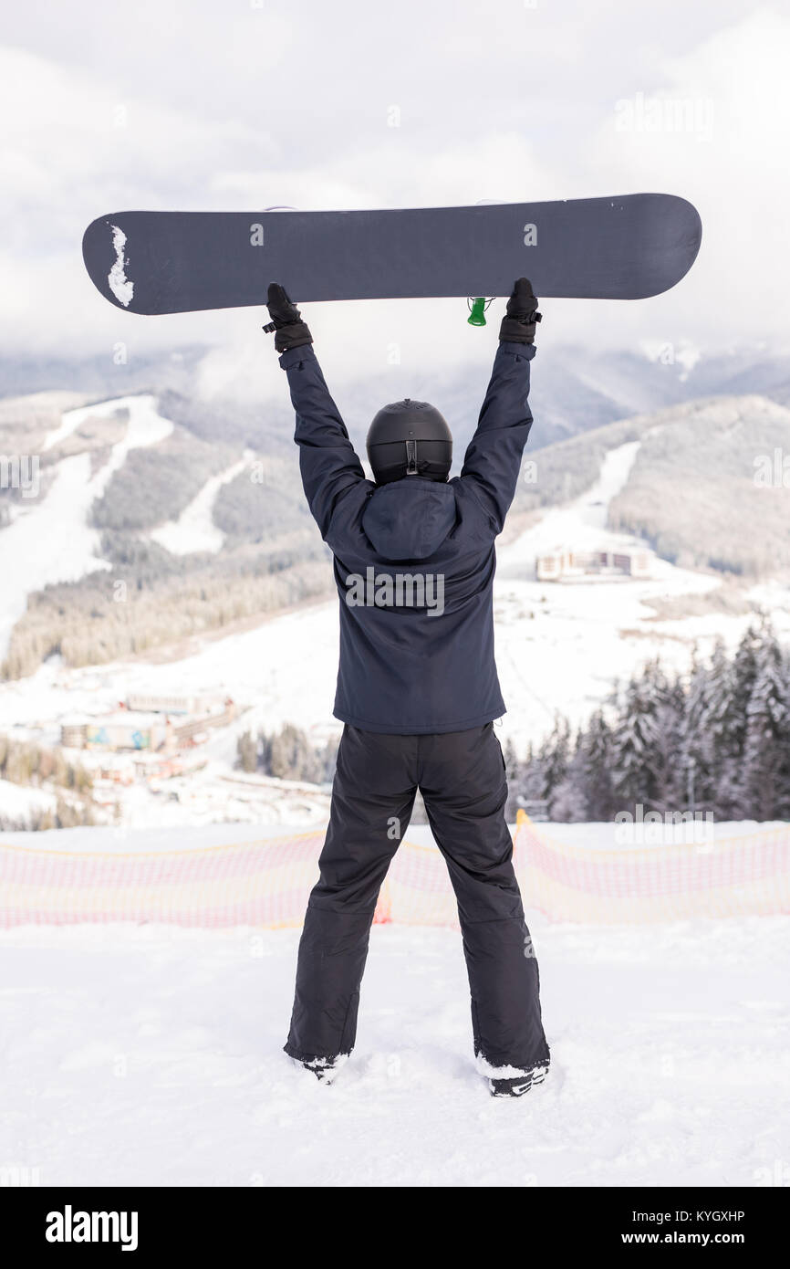 Man standing with snowboard over his head Stock Photo - Alamy