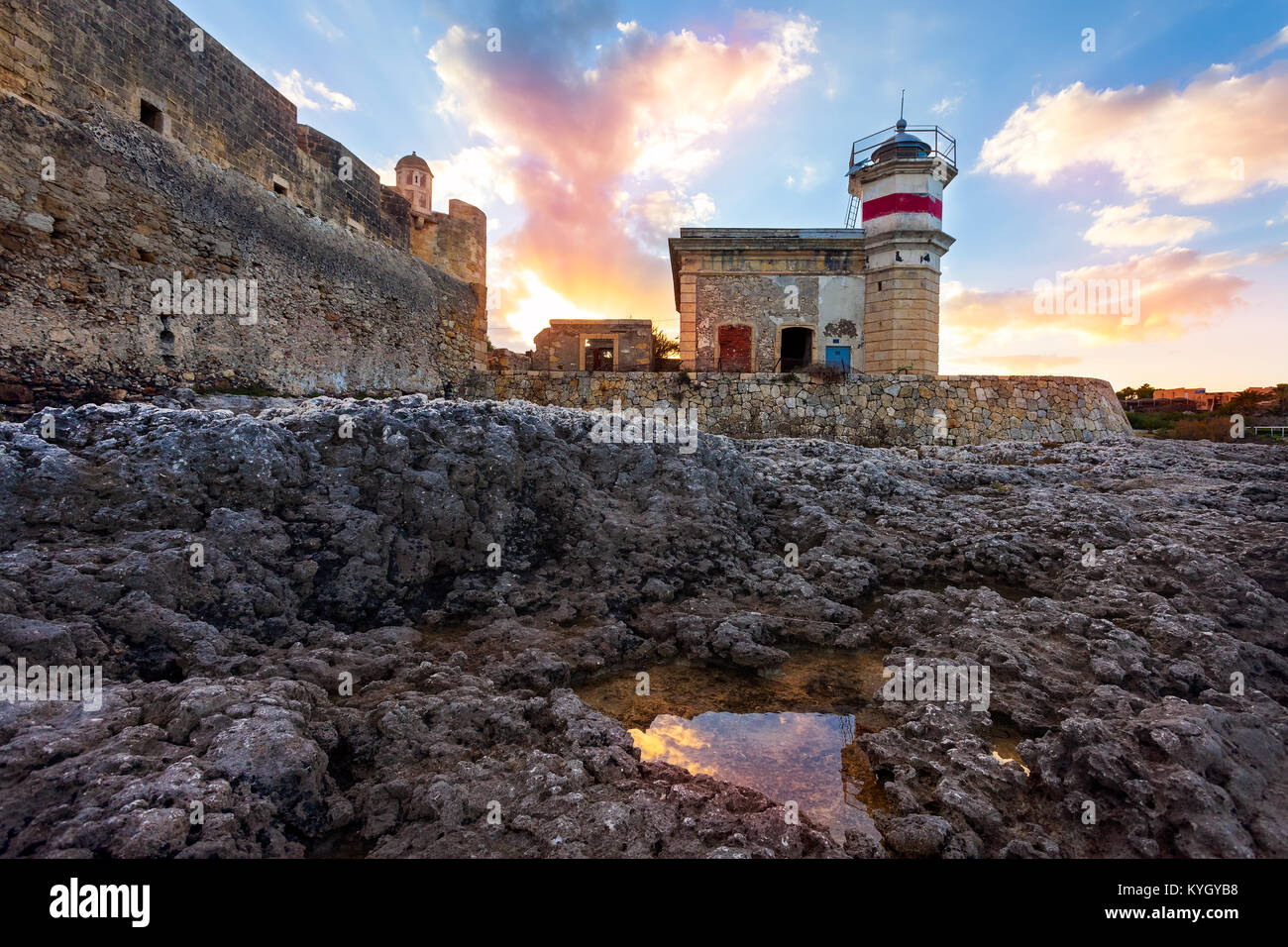 The castle of Brucoli and the little lighthouse reflected in a puddle ...