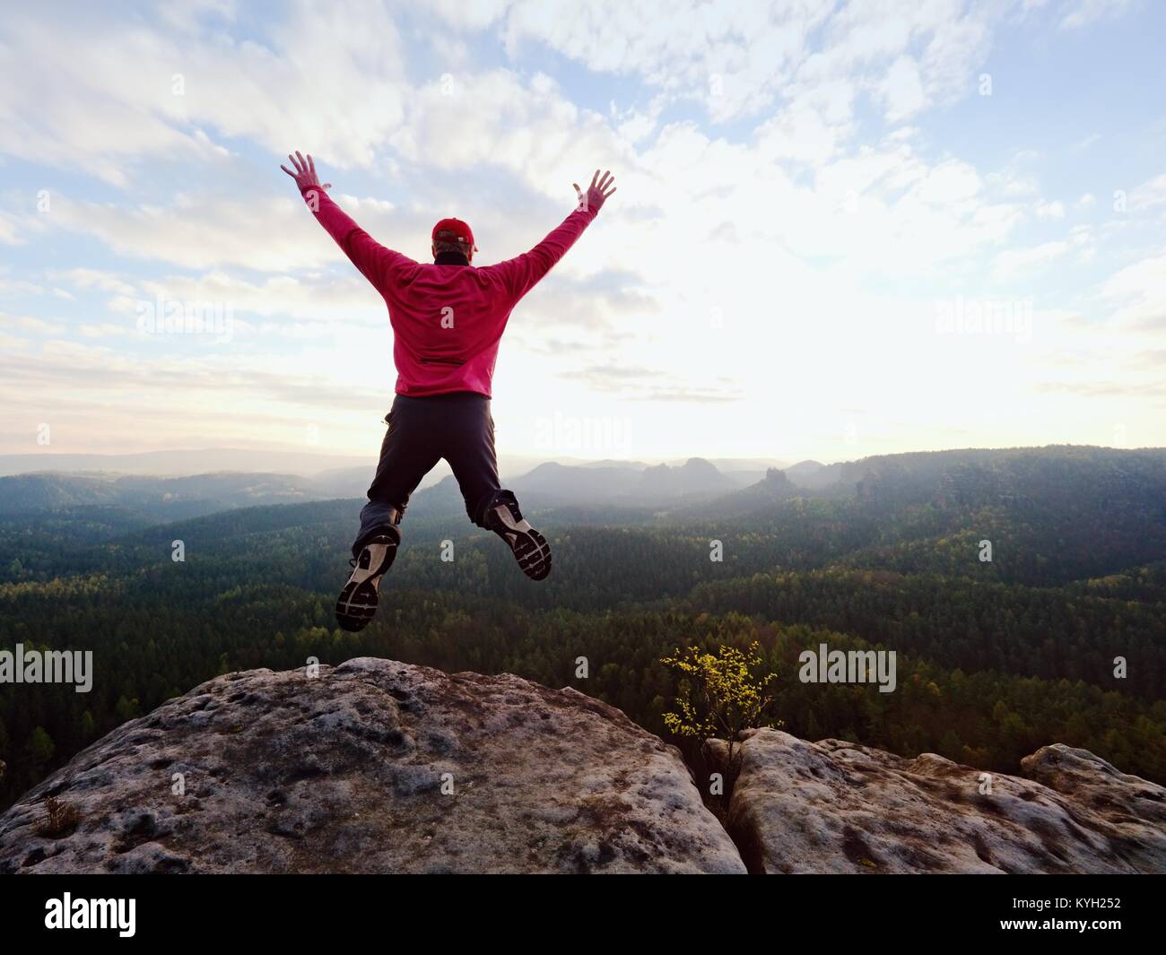 Crazy man. Hiker is jumping on the rocky peak. Wonderful mood in rocky ...