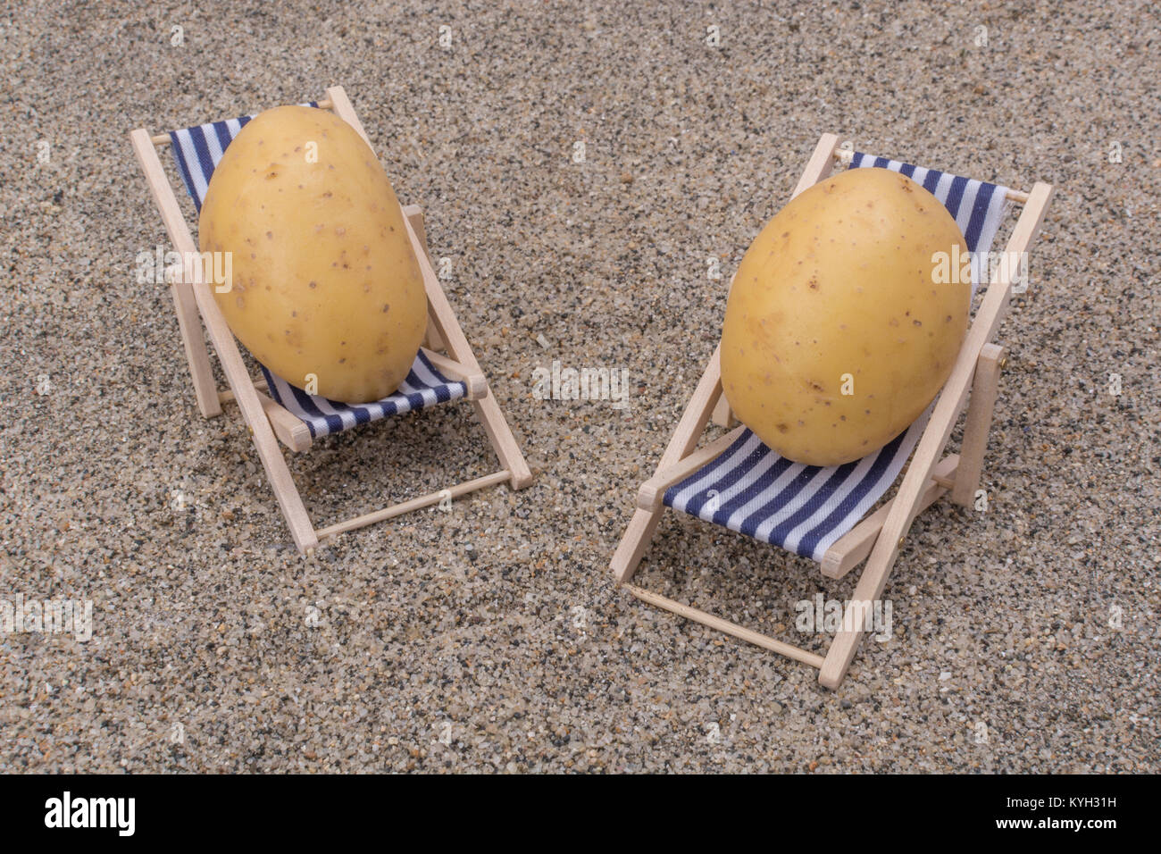 New potatoes on toy deckchair on sand - as visual metaphor for concept ...