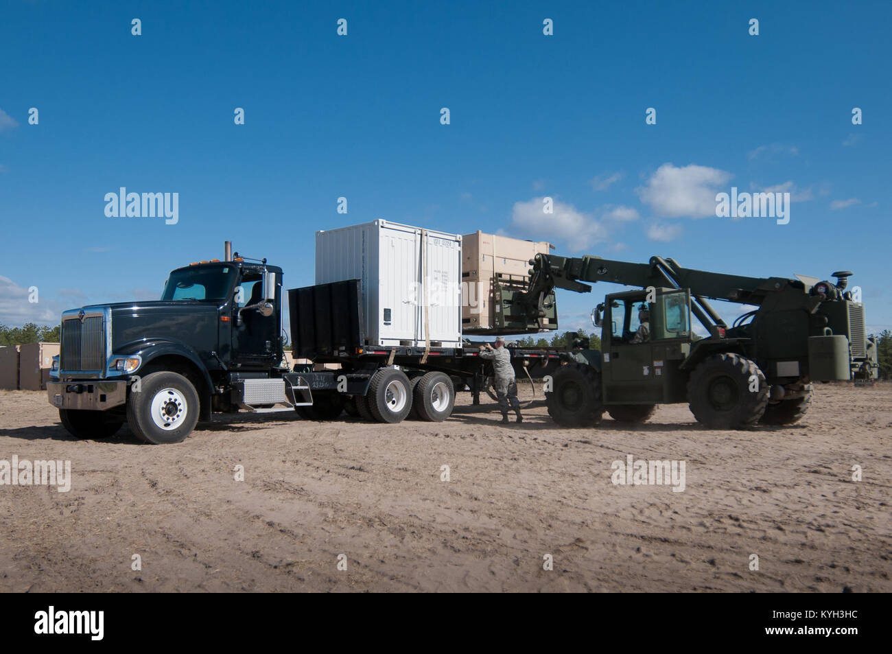 Airmen and Soldiers load cargo containers onto flatbed trailers at the ...