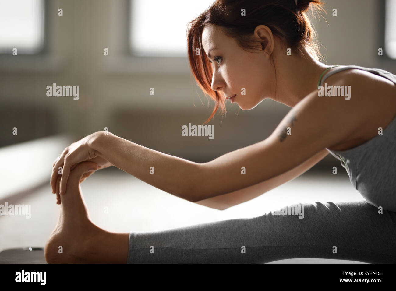 Young sporty woman doing yoga stretching exercise sitting in gym near ...
