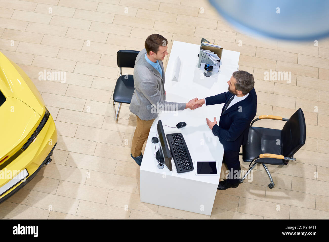 Above view of handsome salesman shaking hands with customer over table ...