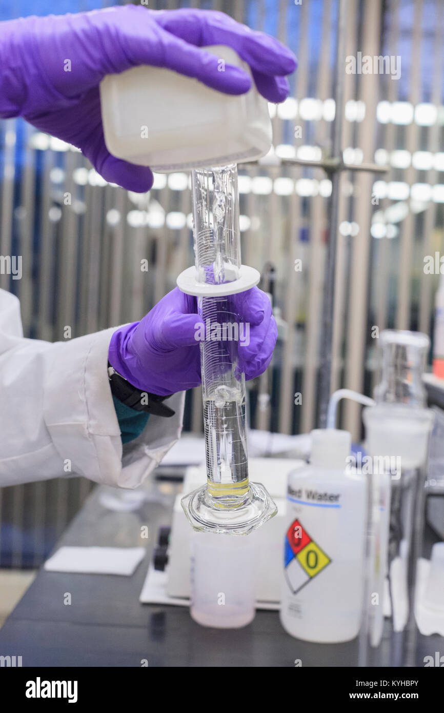 Lab technician adding liquid to graduated cylinder Stock Photo - Alamy