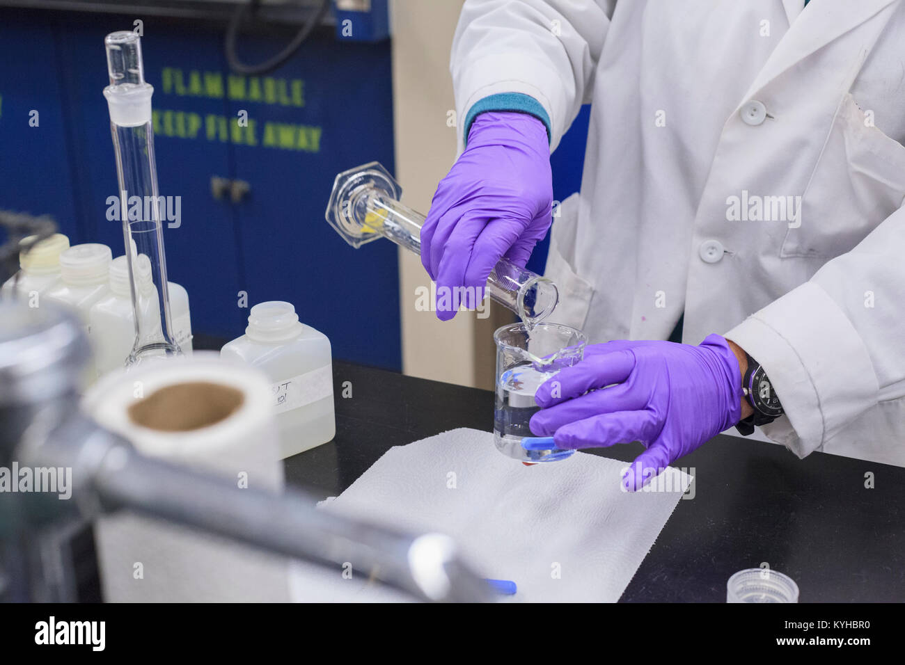 Lab technician adding liquid from graduated cylinder to beaker Stock ...