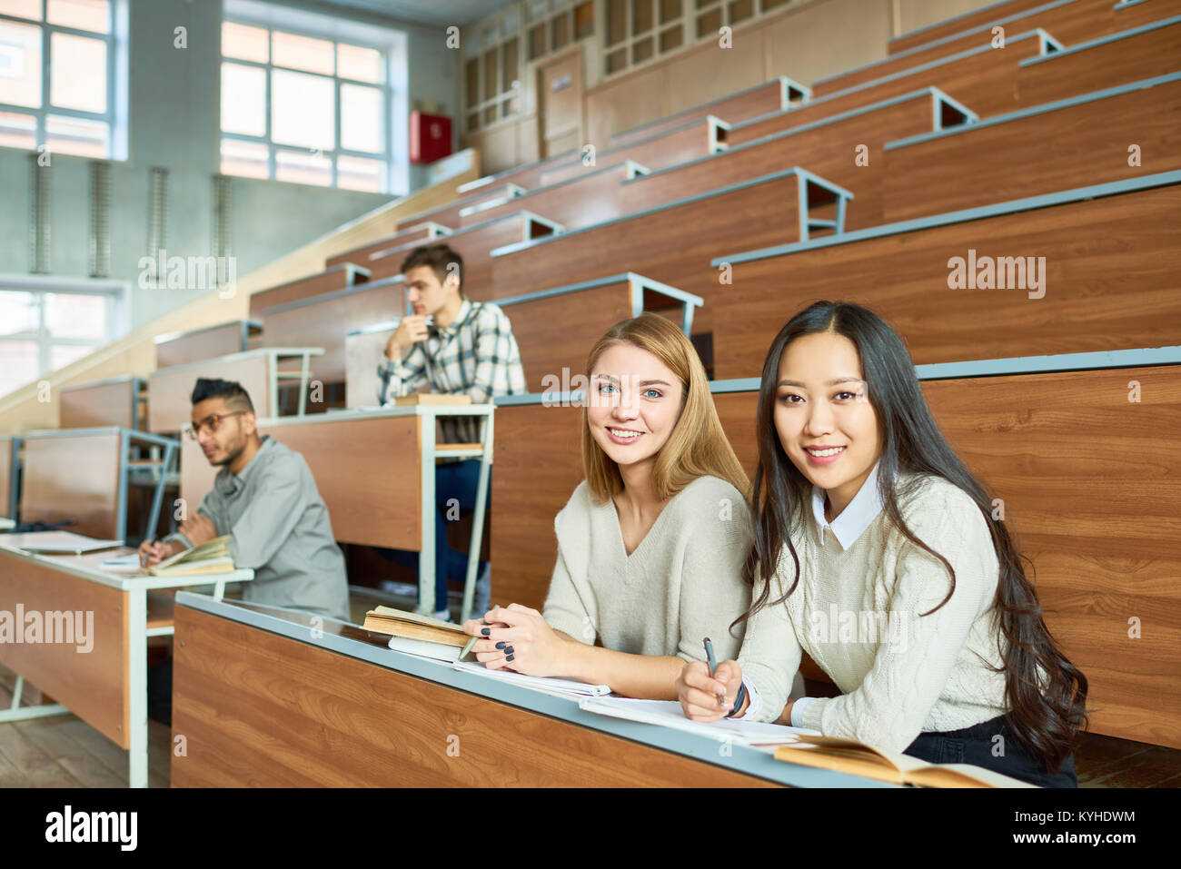 Multi-ethnic group of people sitting at separate tables in lecture hall ...