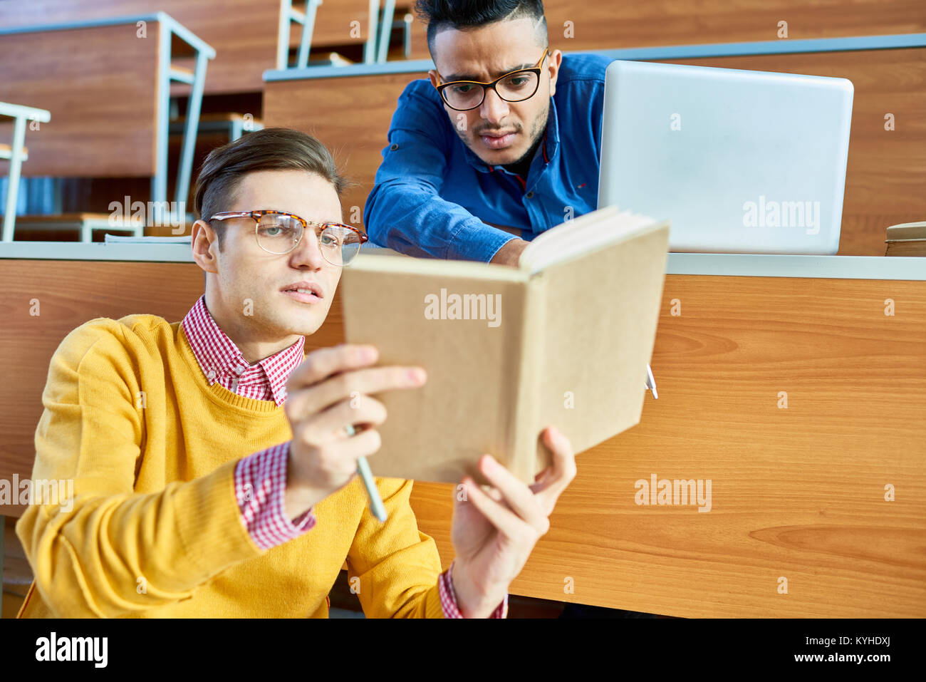 Portrait of two students discussing lecture sitting in auditorium ...