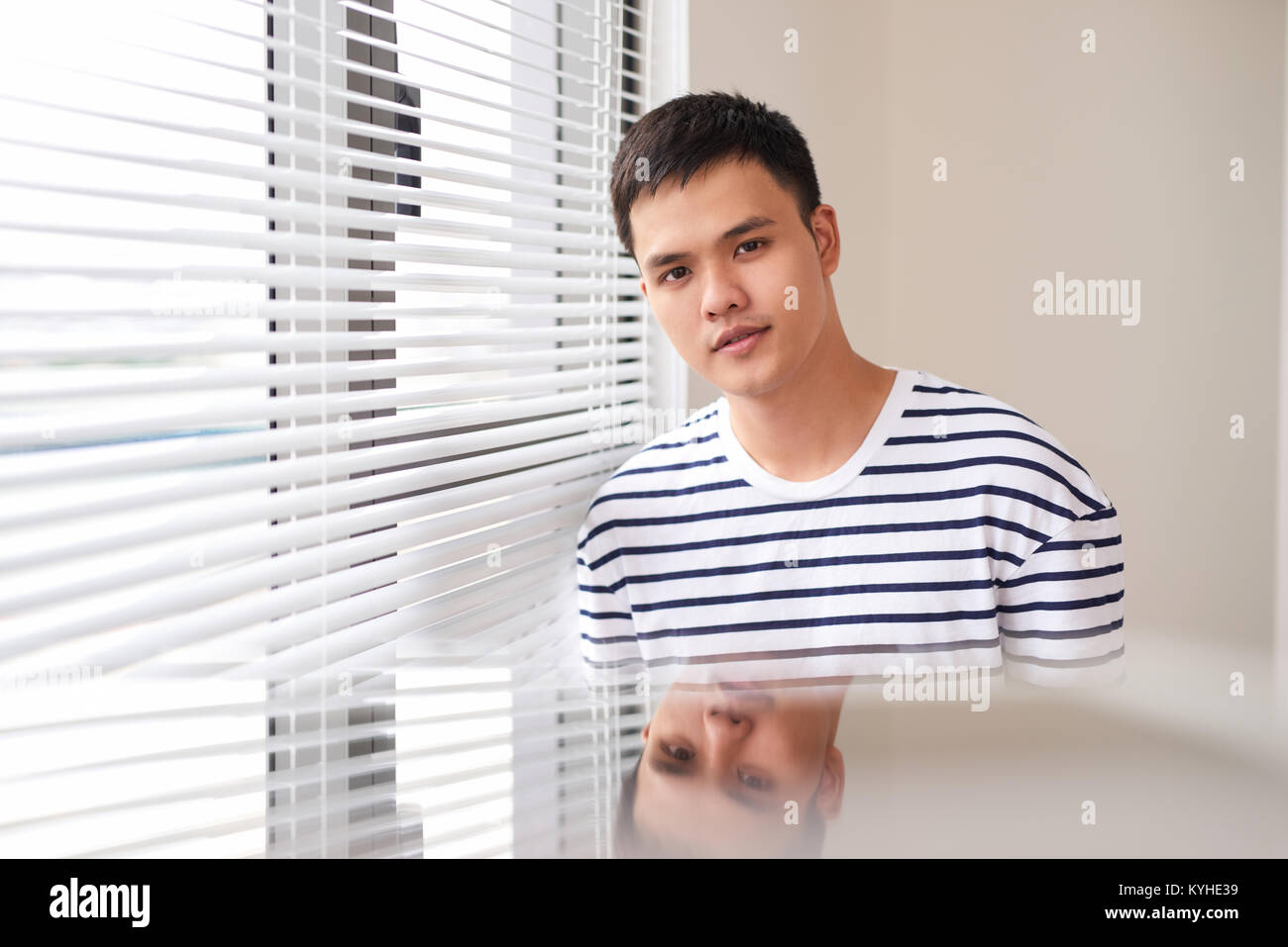 Young man standing by the window in the morning Stock Photo - Alamy
