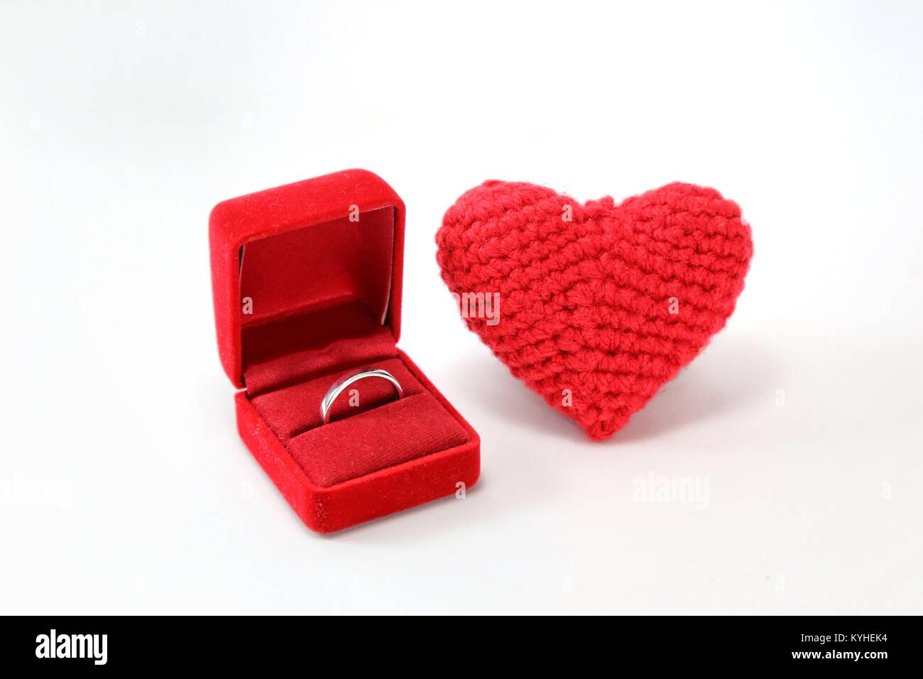 Red crocheted heart with wedding ring in a box on isolated white ...