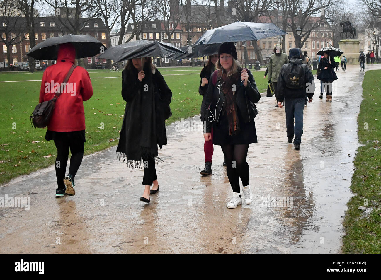 People shelter under umbrellas in pouring rain as they commute to work ...