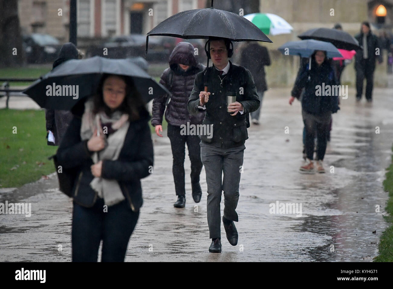 People shelter under umbrellas in pouring rain as they commute to work ...